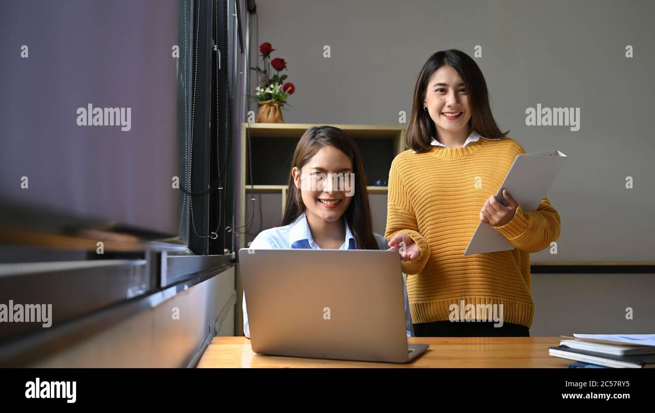 Portrait two women are together with a computer laptop and document ...