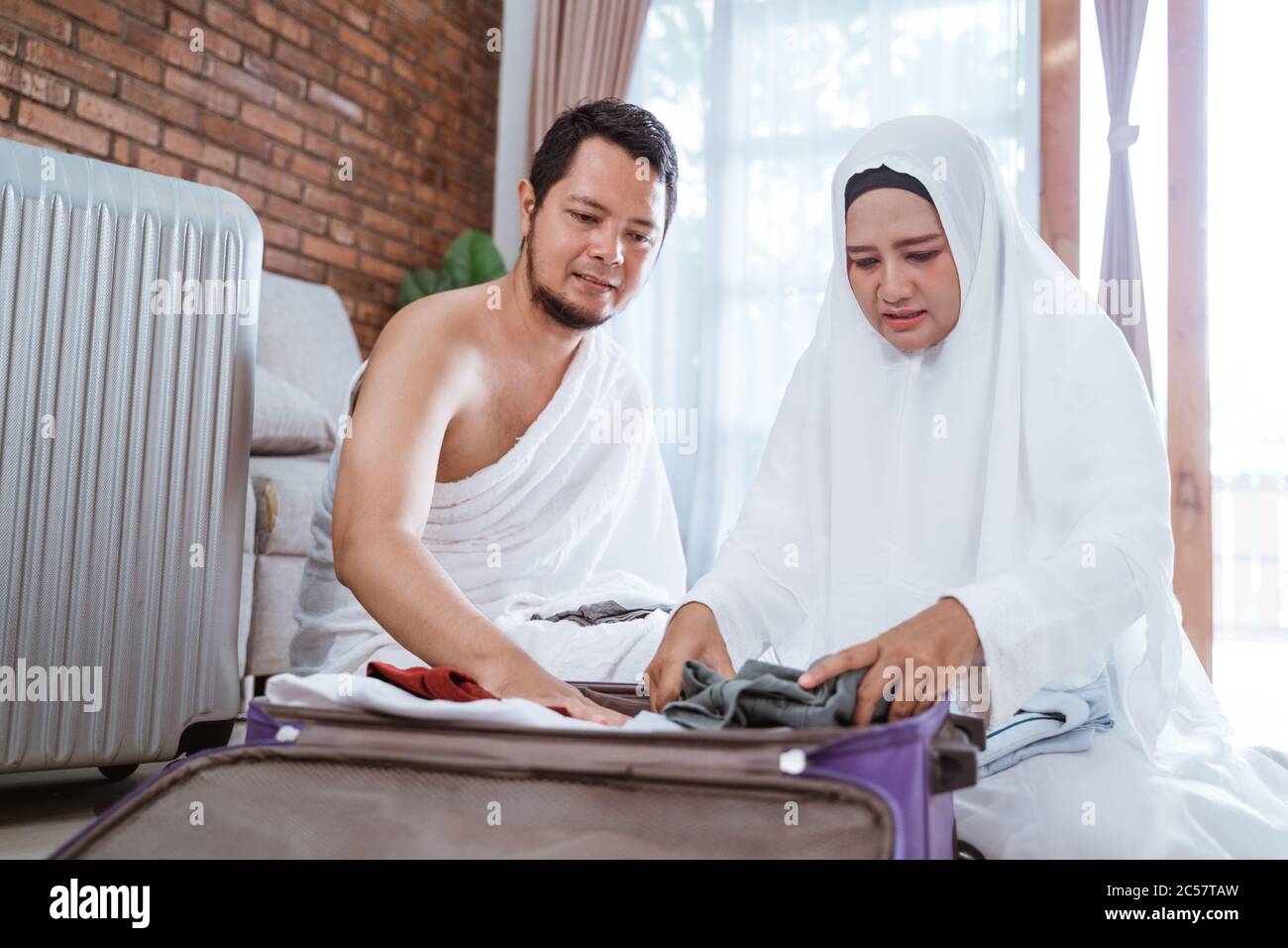 muslim family in white traditional clothes preparing luggage before ...