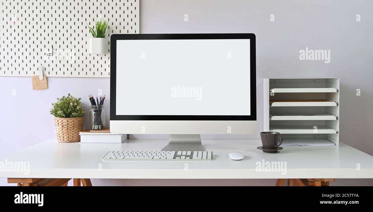 A white working desk is surrounding by a white blank screen computer ...