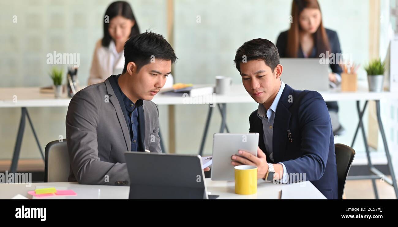 Businessmen are working together with computer tablets while sitting at ...