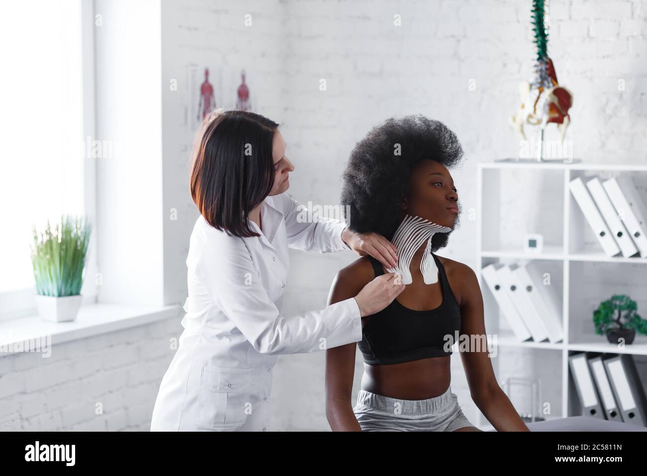 Kinesiology taping. Physiotherapist applying kinesiology tape to patient neck. Therapist ...