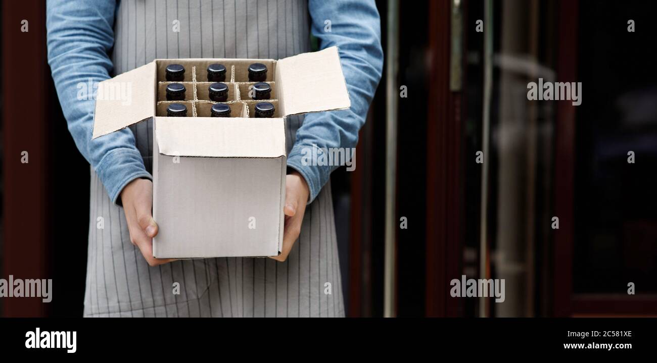 Beer for party at weekend. Bartender holds open cardboard box with ...