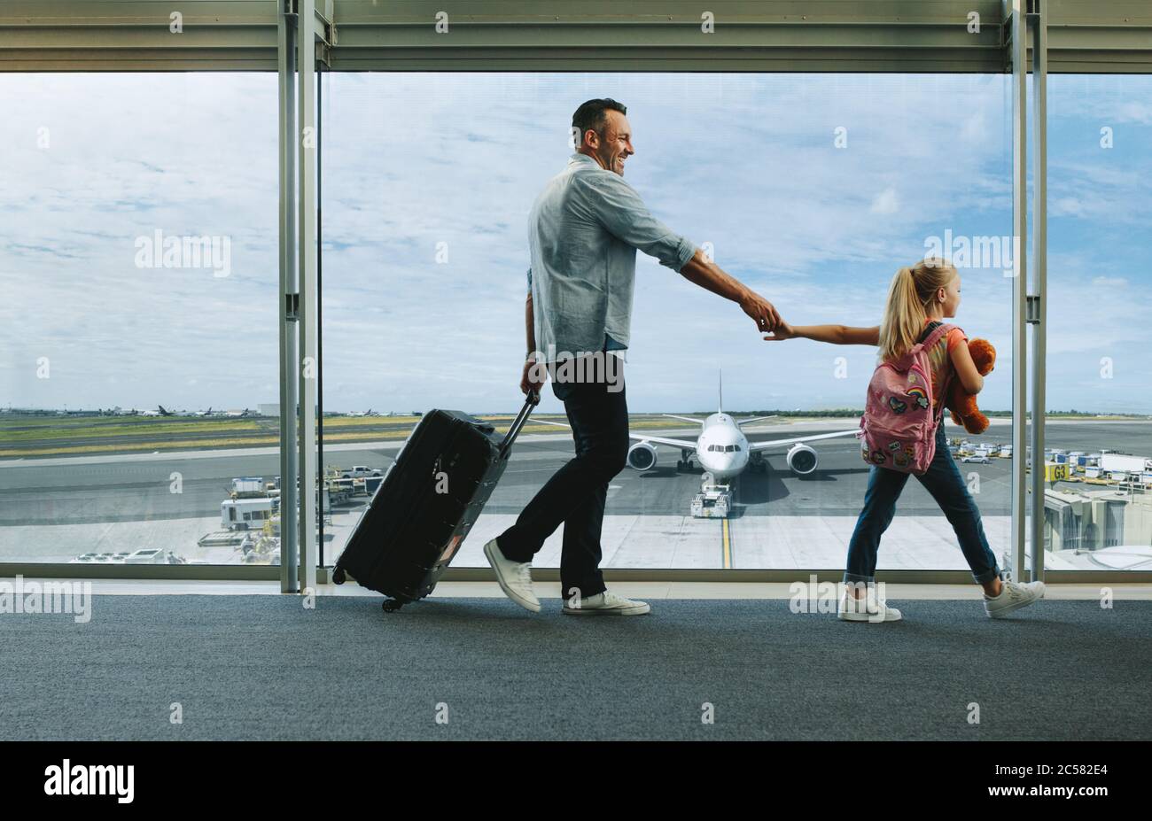 Girl holding hand of her father and walking to board their flight at ...
