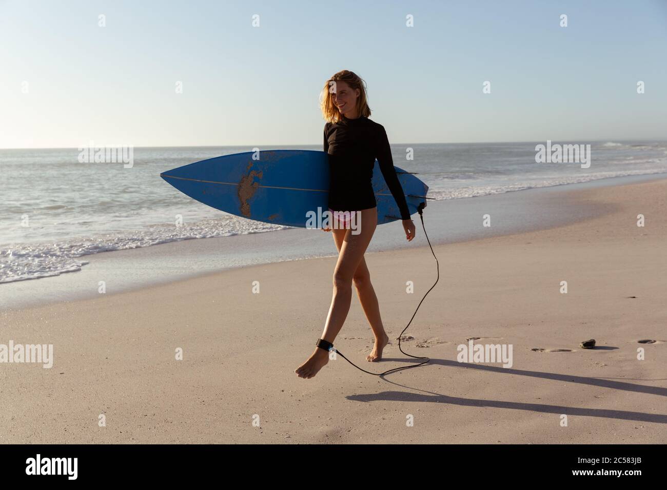 Woman with surfboard walking on the beach Stock Photo - Alamy