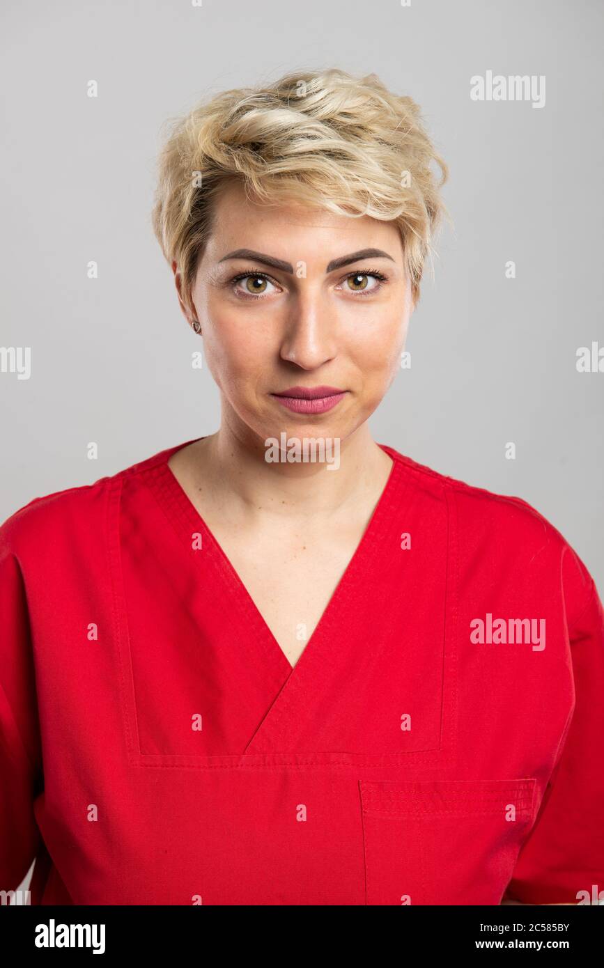 Portrait of young attractive female nurse posing at camera on grey ...