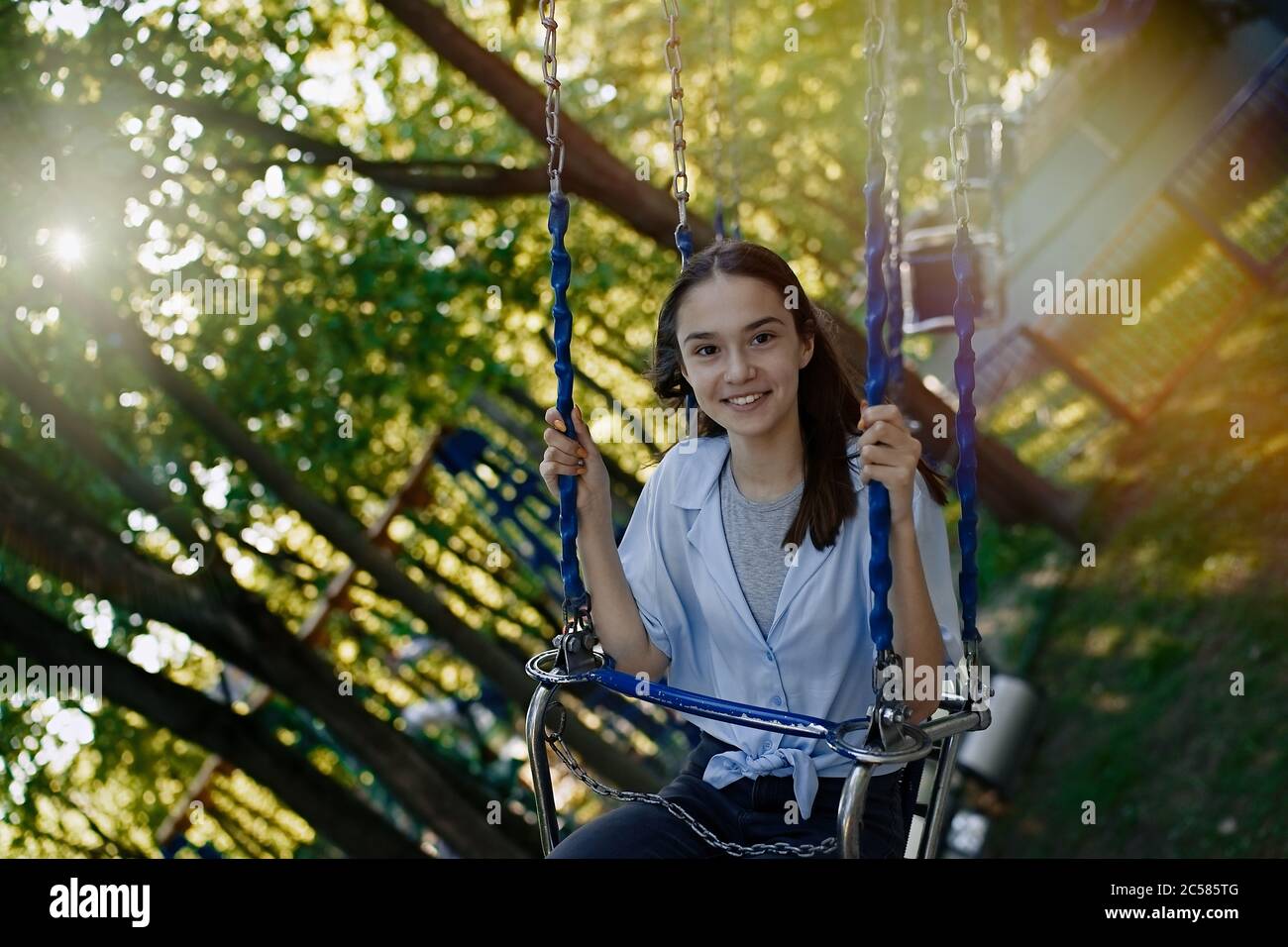 Happy child teenage girl riding chain carousel swing at amusement park ...