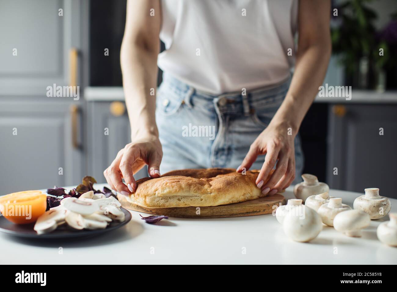 Girl breaks bread with her hands in the bright kitchen. Healthy food ...