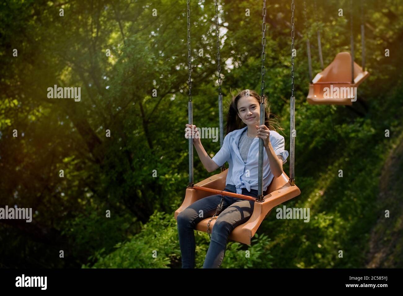 Happy child teenage girl riding chain carousel swing at amusement park ...