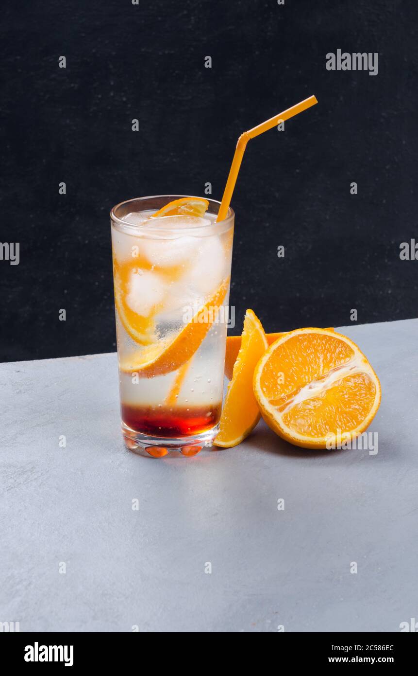 Orange alcohol cocktail with orange fruit slice on gray and black ...
