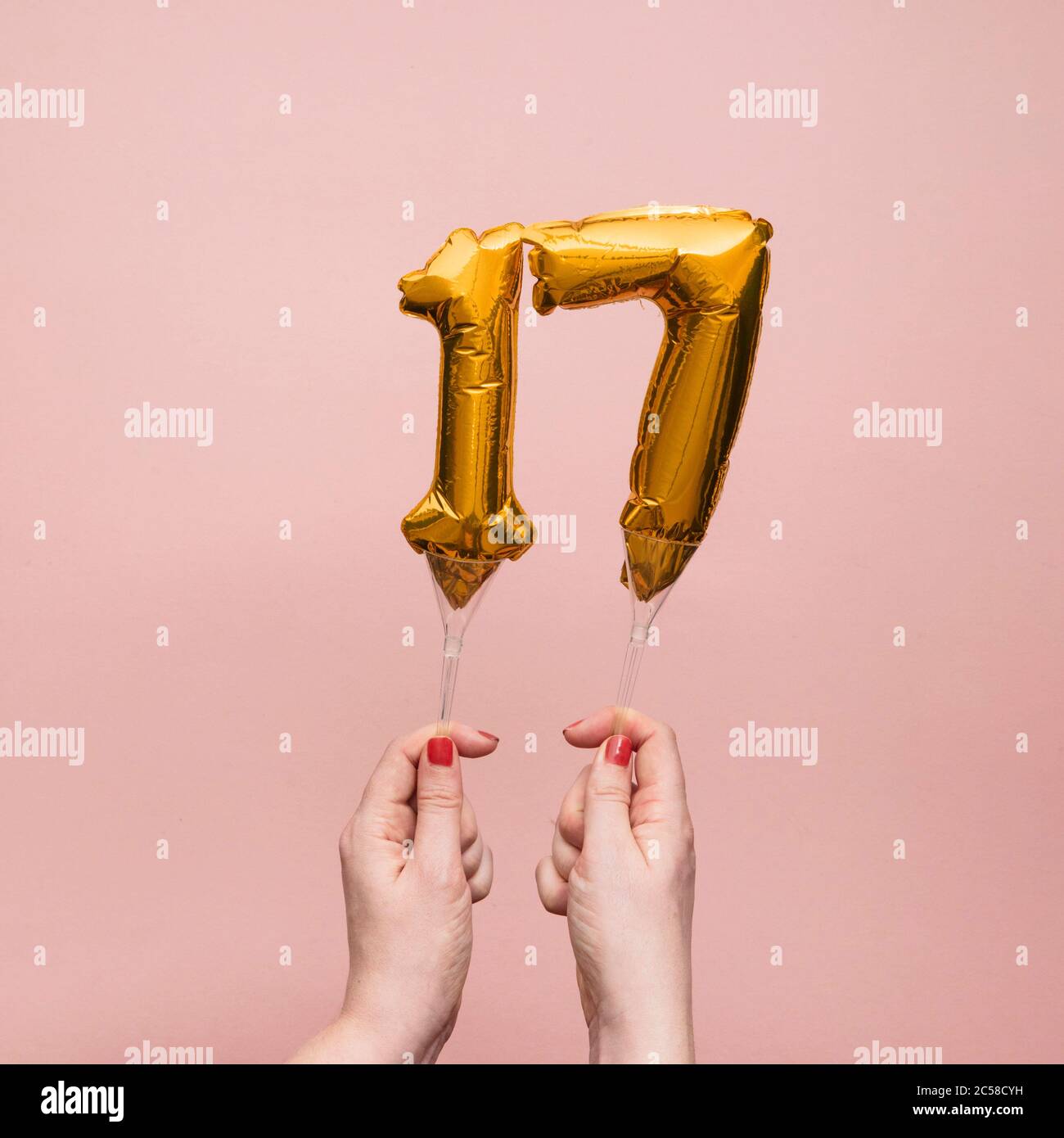 Female hand holding a number 17 birthday anniversary celebration gold ...