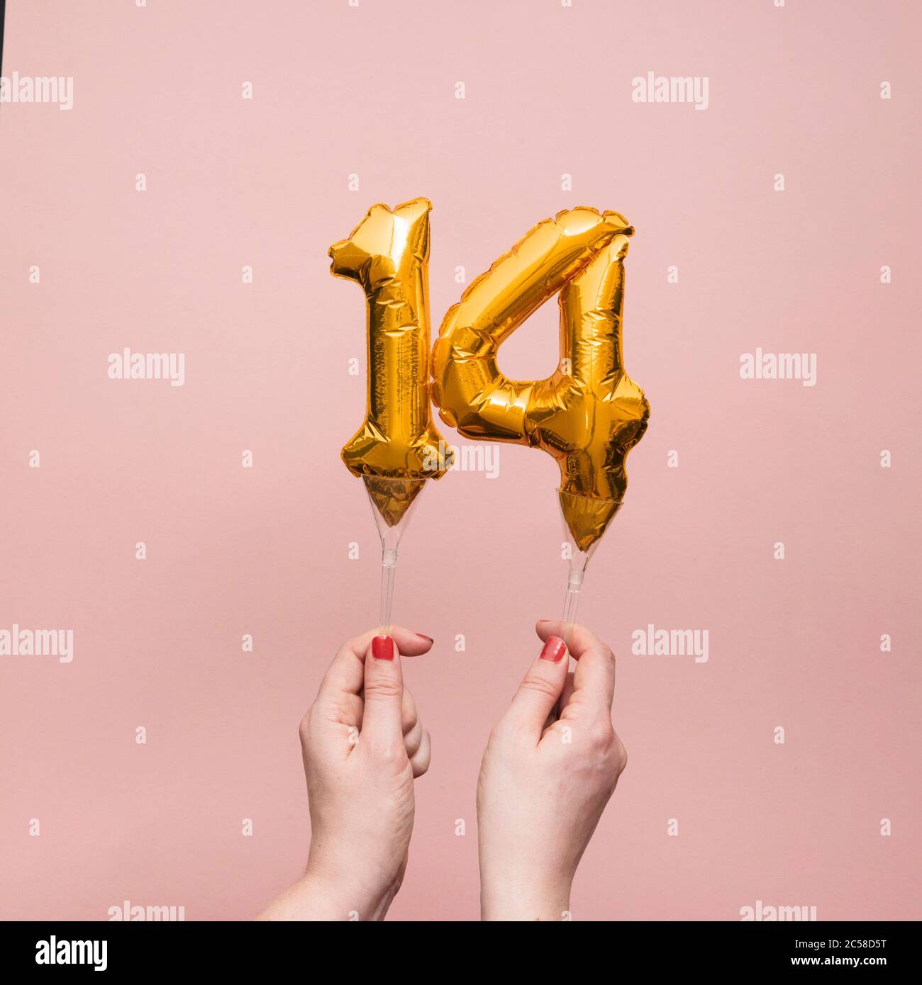 Female hand holding a number 14 birthday anniversary celebration gold ...