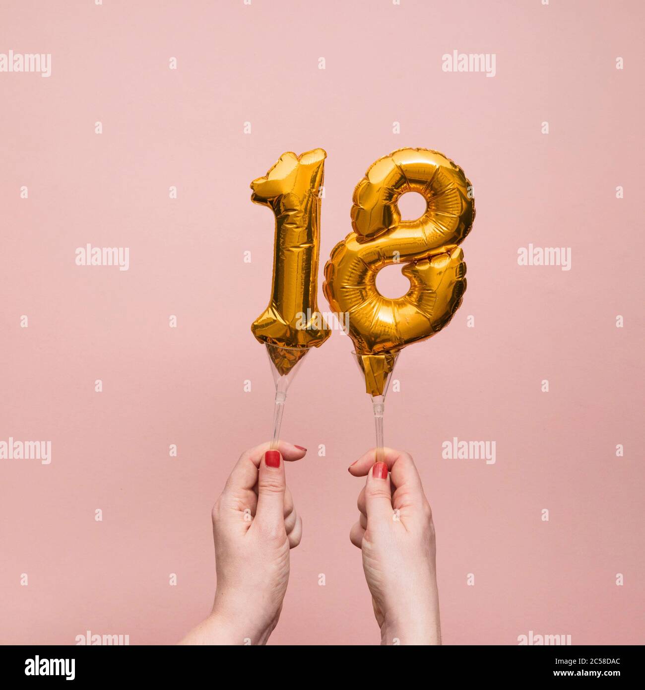 Female hand holding a number 18 birthday anniversary celebration gold ...