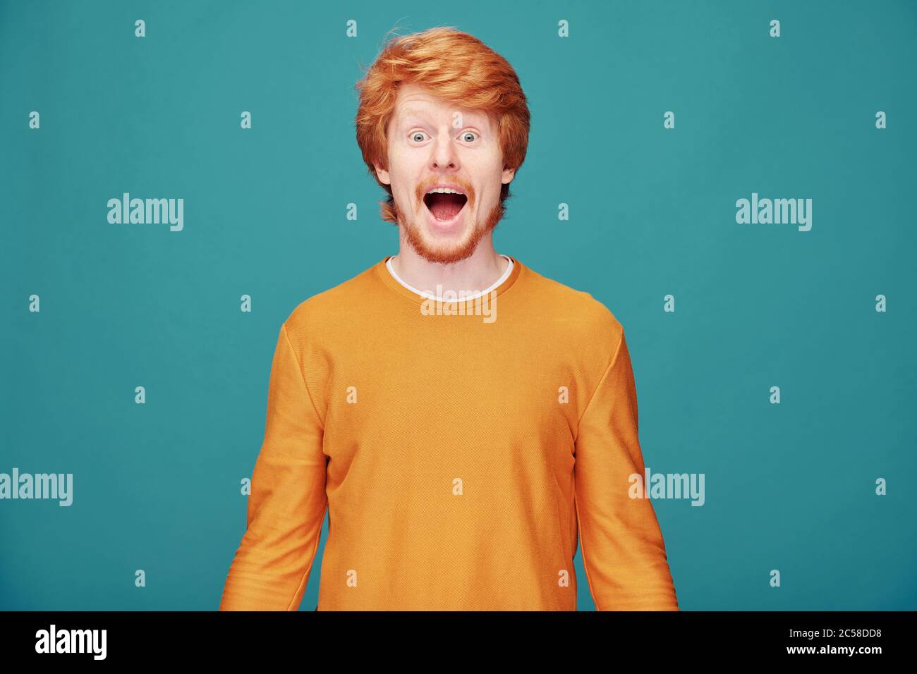 Portrait of ecstatic emotional redhead man with bead screaming ...