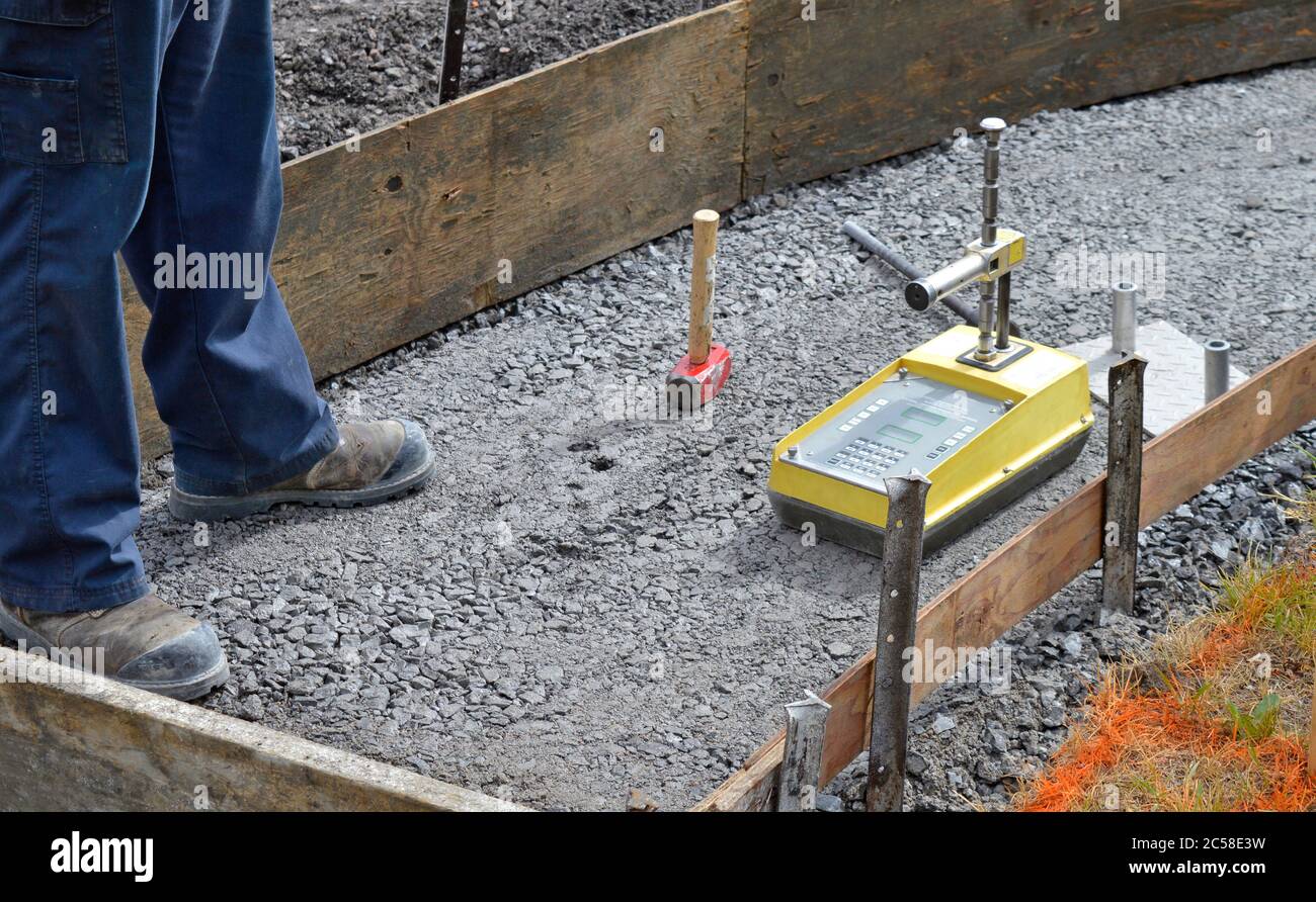 A worker tests the compaction of crushed stone before installing a new ...