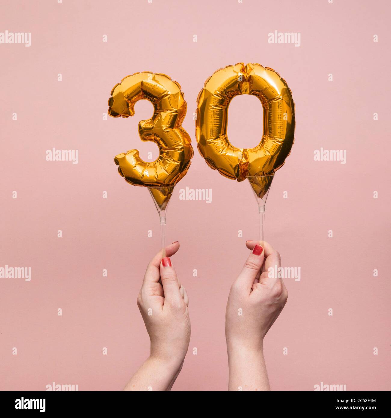 Female hand holding a number 30 birthday anniversary celebration gold ...