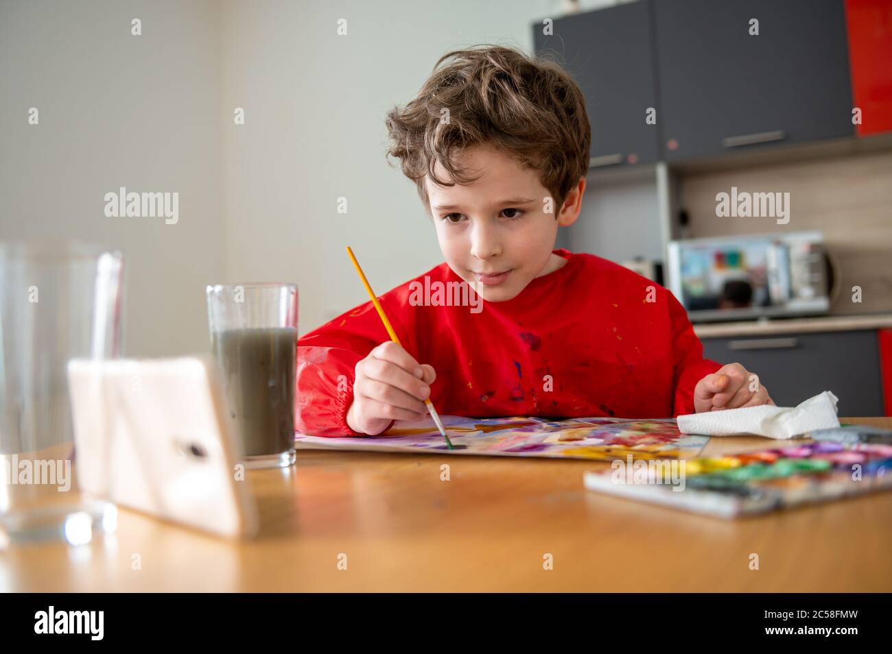 Boy drawing diligently using online lessons on smartphone at home Stock ...