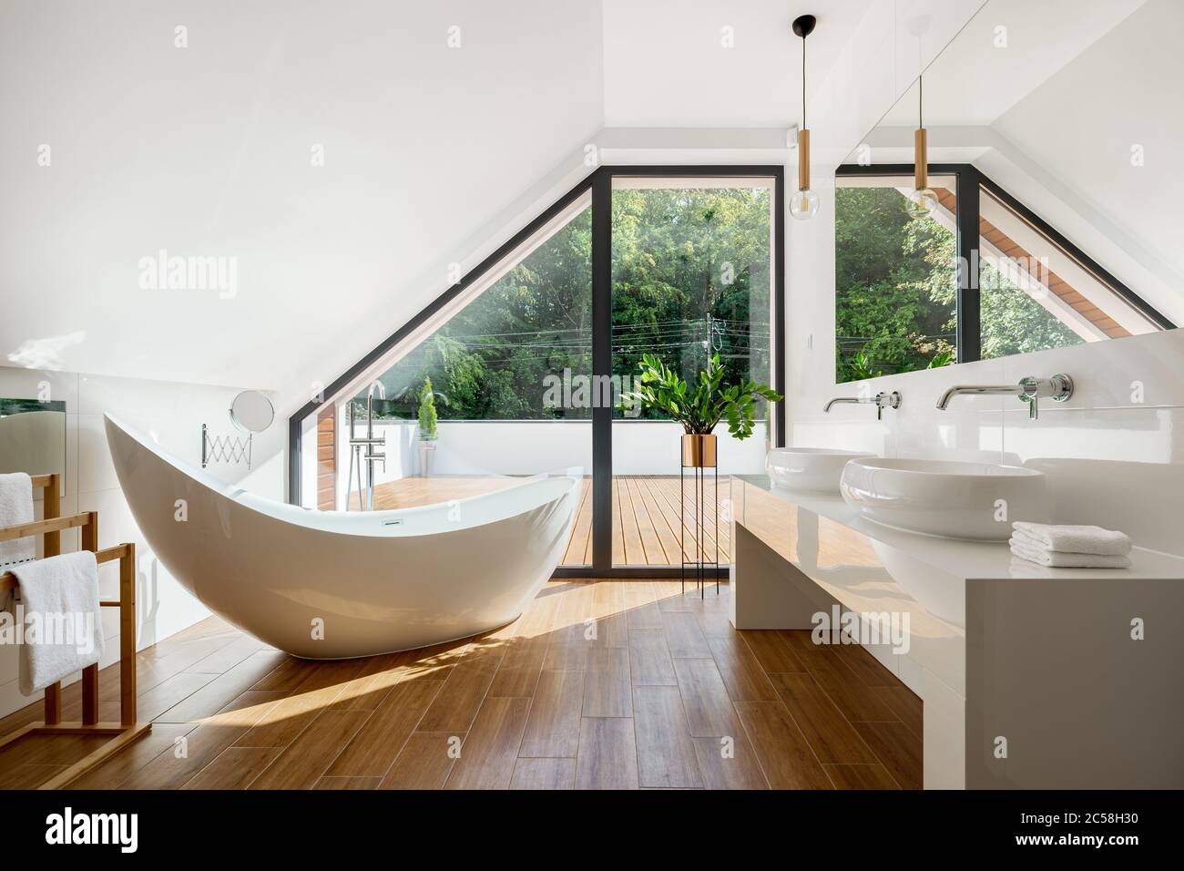 Elegant attic bathroom with stylish bathtub, wooden floor and balcony ...