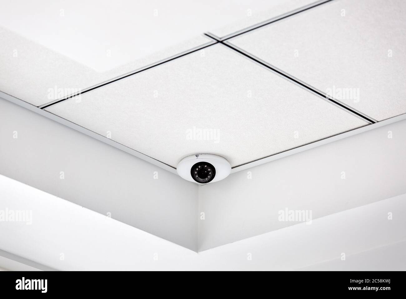 CCTV camera in the corner on a white suspended ceiling, security system ...