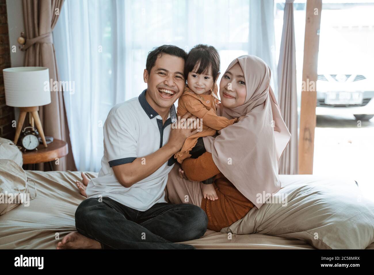 Muslim families smile happily when hugging while sitting on the bed ...