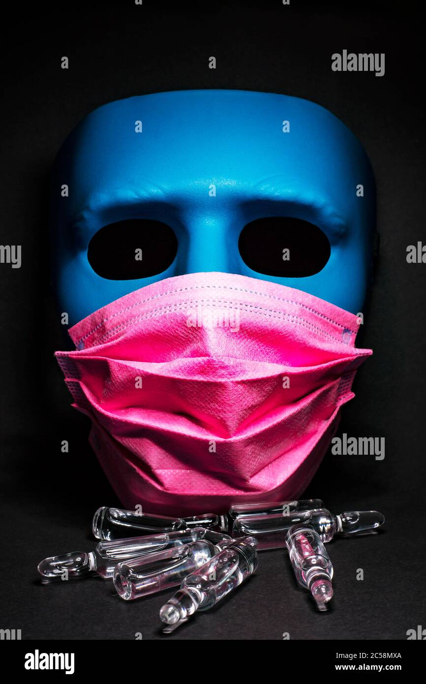 Medical pink mask put on a blue mask. black background Stock Photo - Alamy
