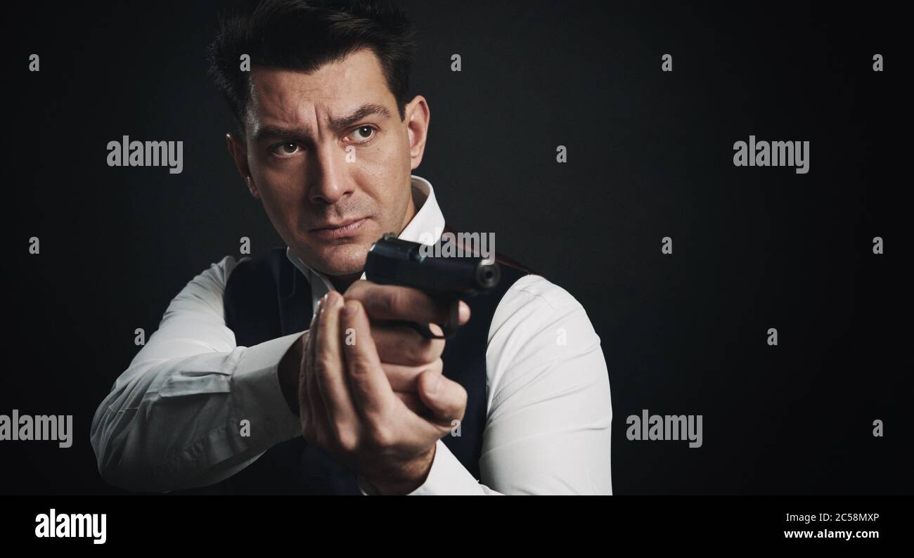 Serious man is holding a gun over black background Stock Photo - Alamy