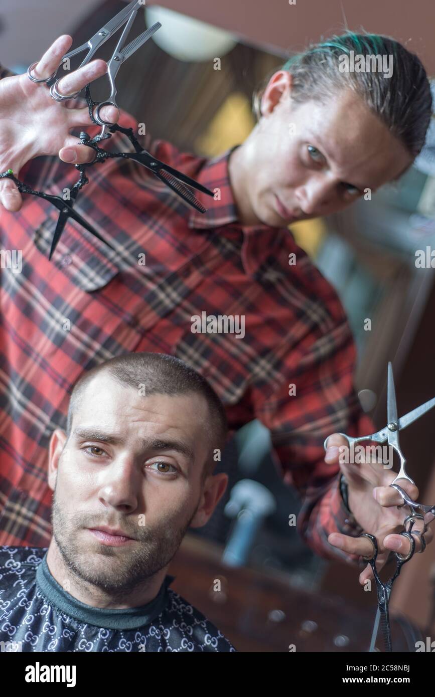 hairdresser a young guy with many scissors in his hand, cuts with a ...