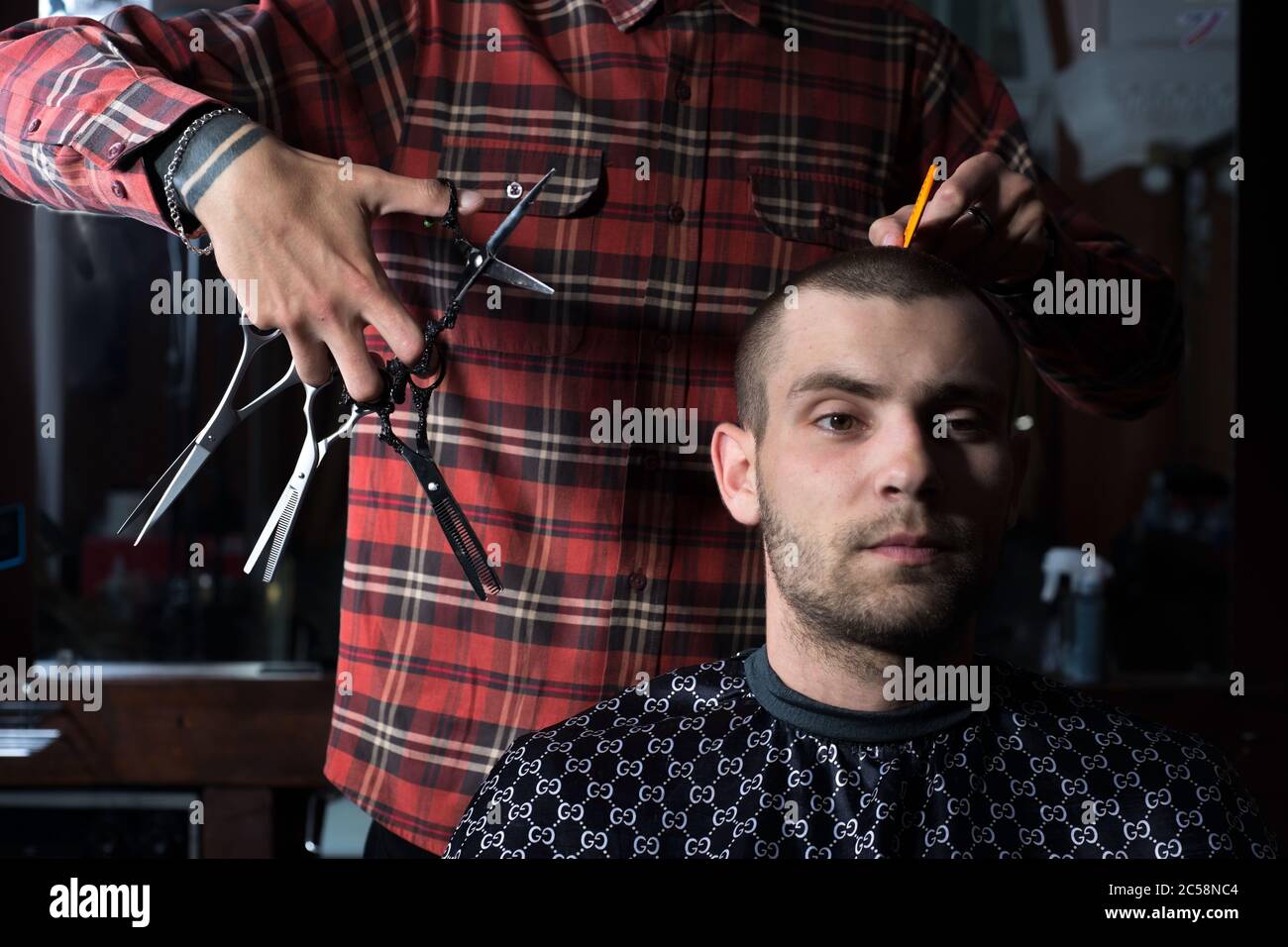 hairdresser a young guy with many scissors in his hand, cuts with a ...