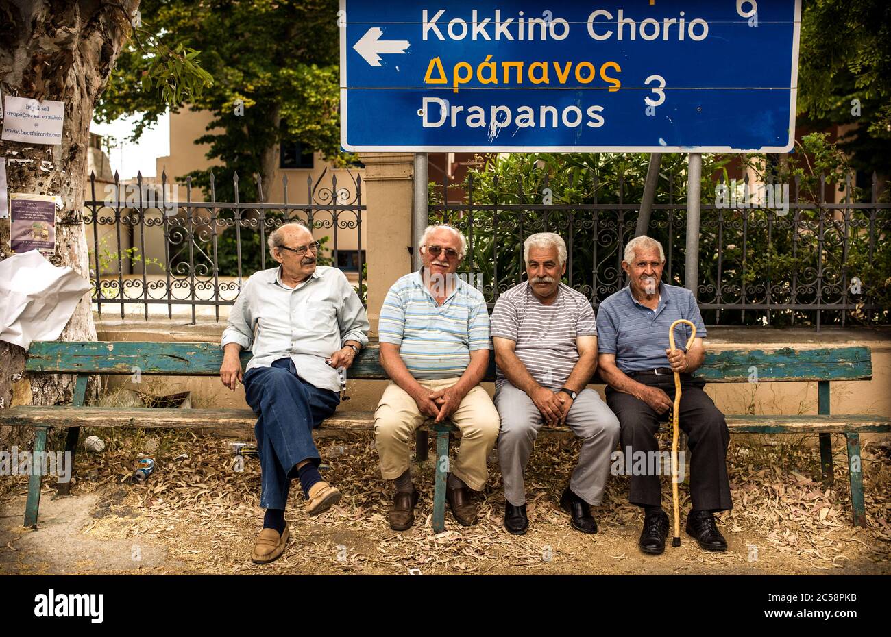 Four Greek men sitting on a bench by the village church at Kefalas in ...