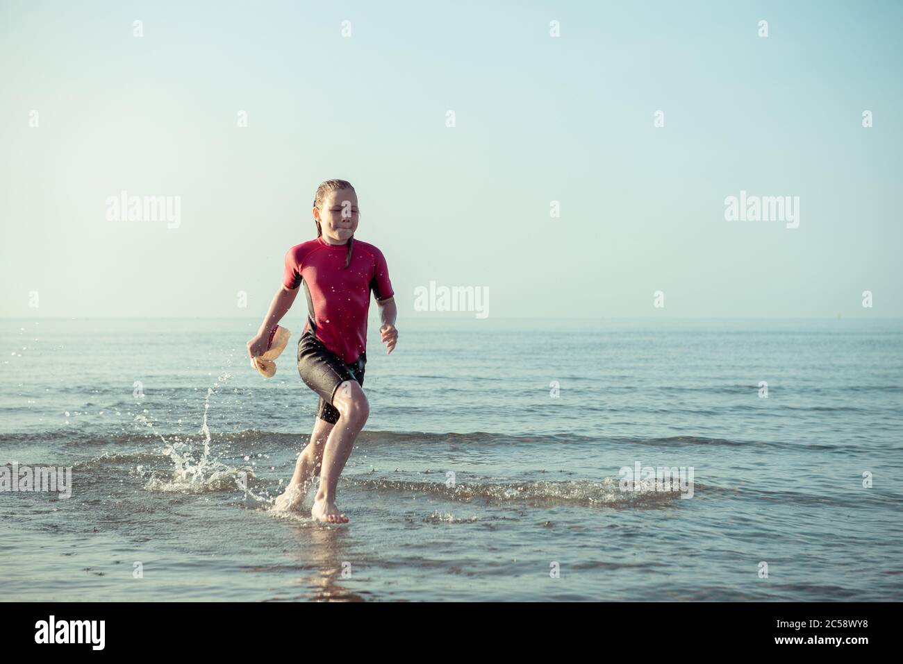 Cute happy teen child girl running and having fun in water in Baltic ...