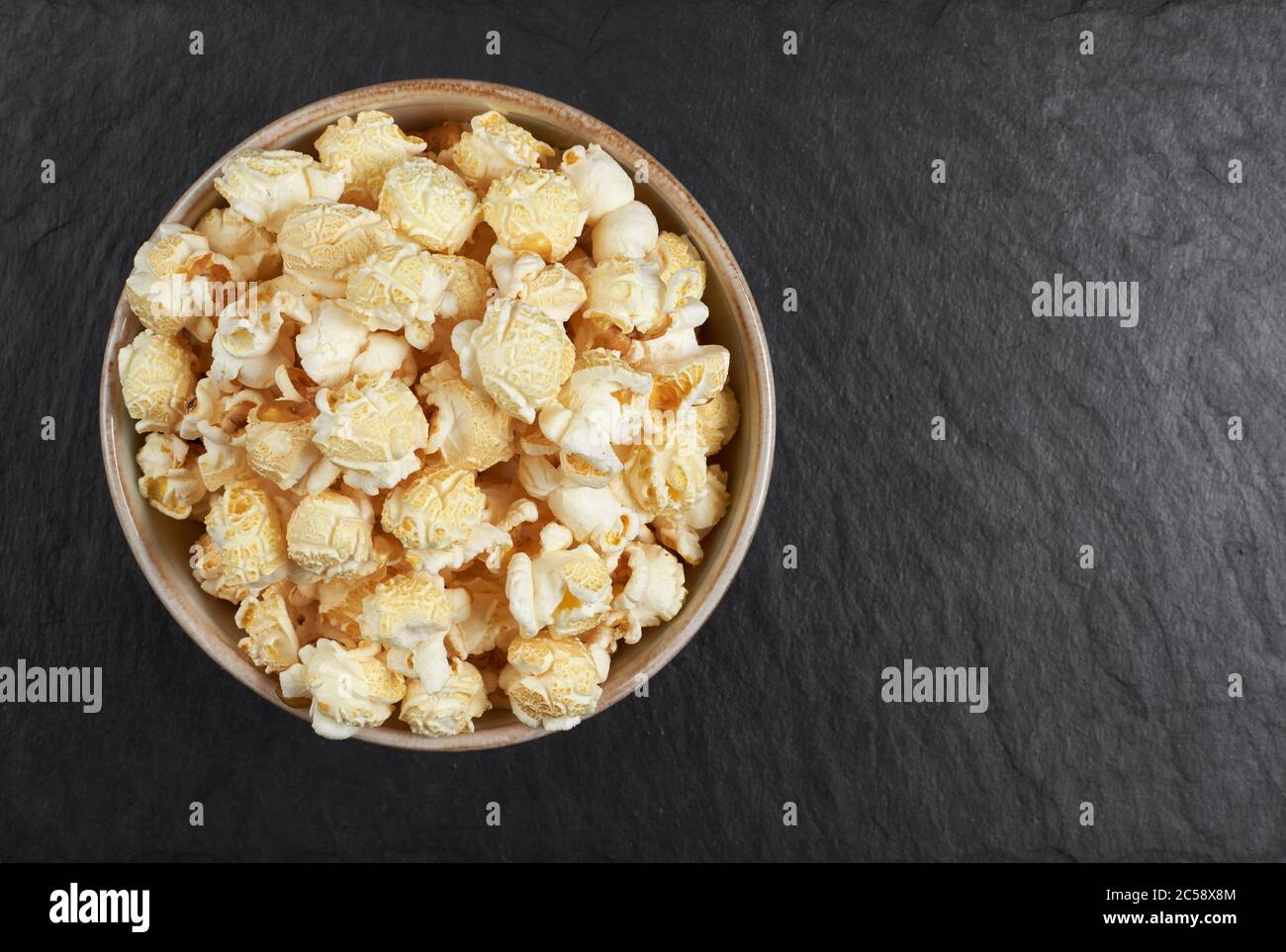 Bowl of popcorn on a stone background. Top view Stock Photo - Alamy