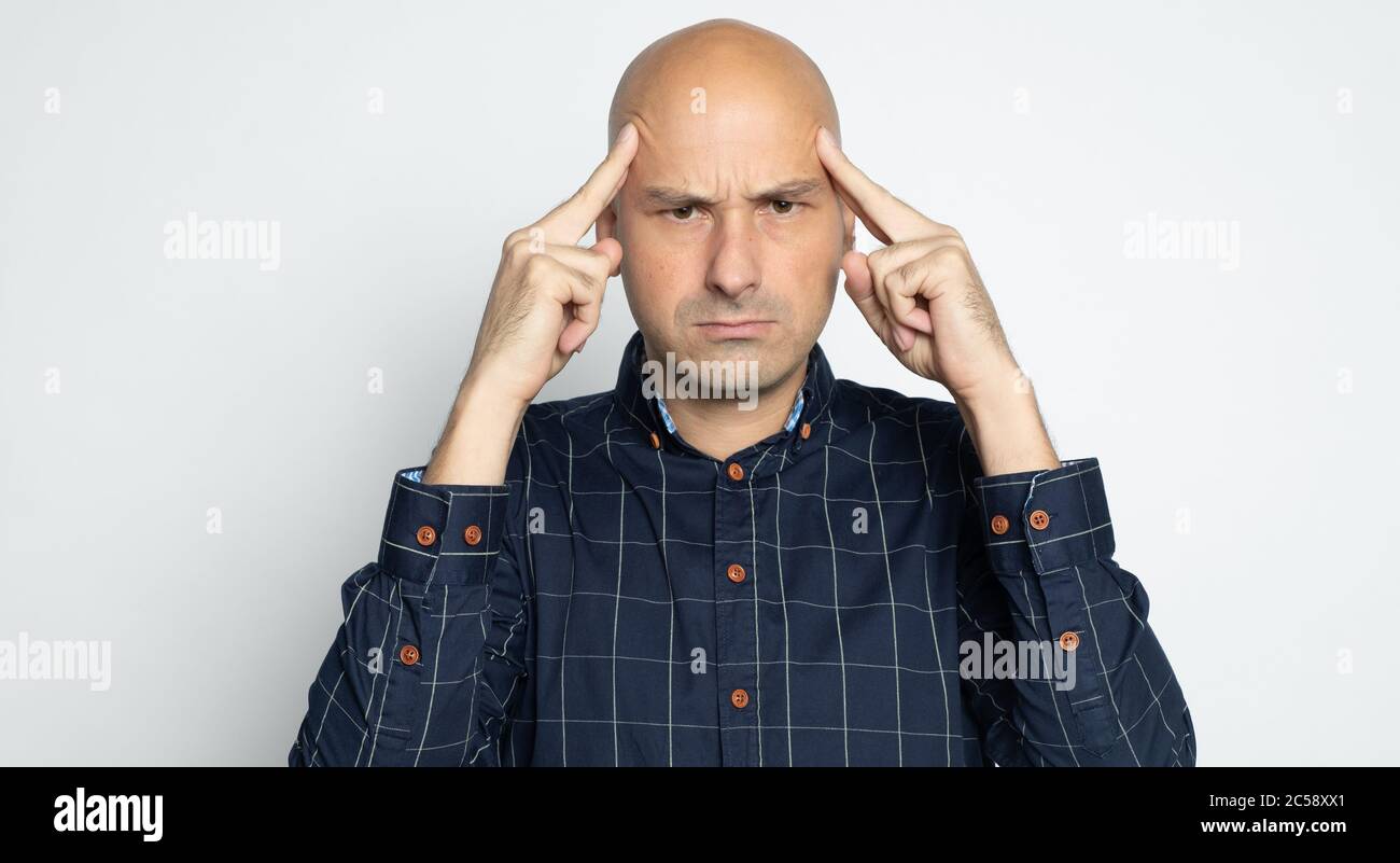 serious bald man is thinking isolated on grey studio wall Stock Photo ...