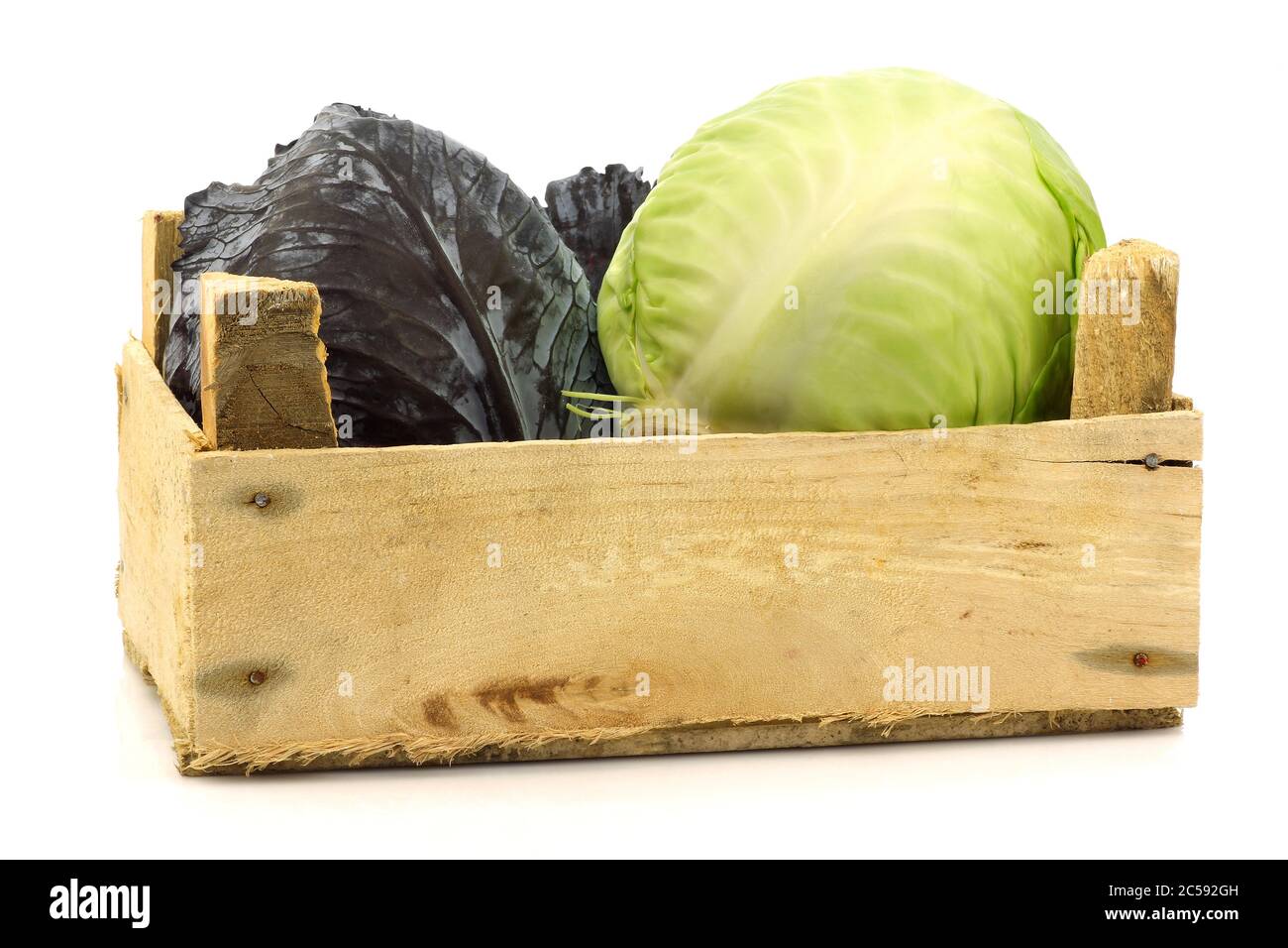 freshly cut red and white cabbage in a wooden crate on a white ...