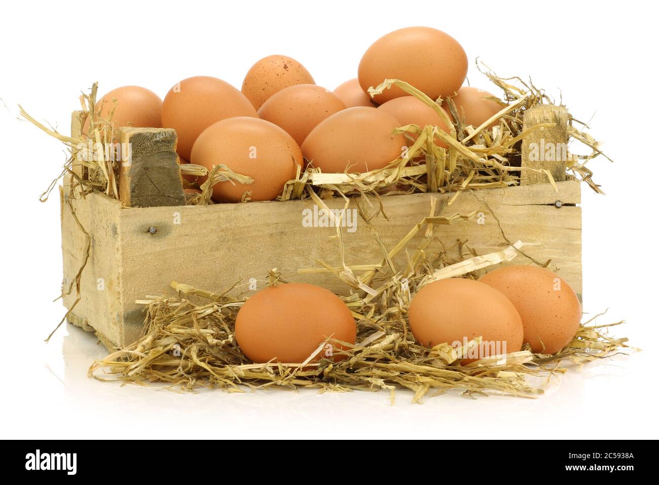 bunch of fresh brown eggs and some straw in a wooden crate on a white ...