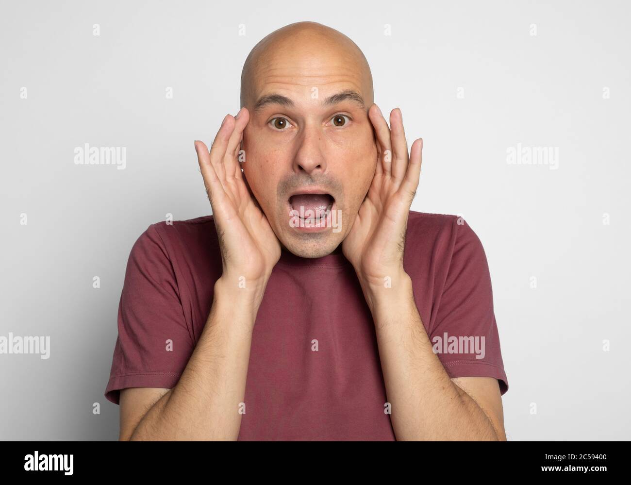 excited bald man looking at camera with open mouth isolated over grey ...
