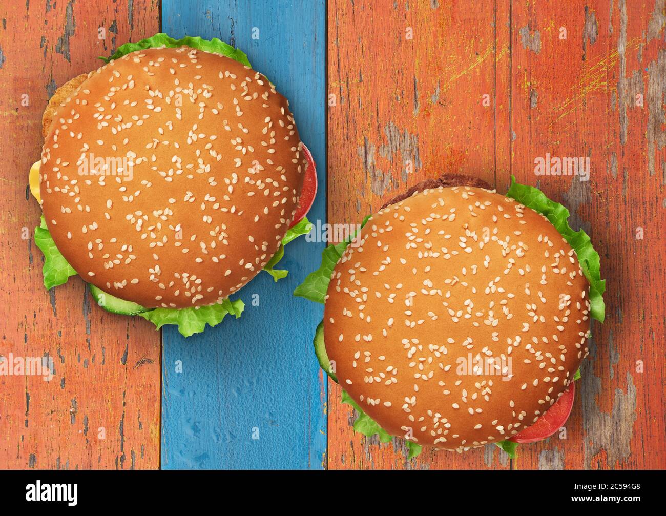Two burgers on a color painted old wood plank background. Top view ...