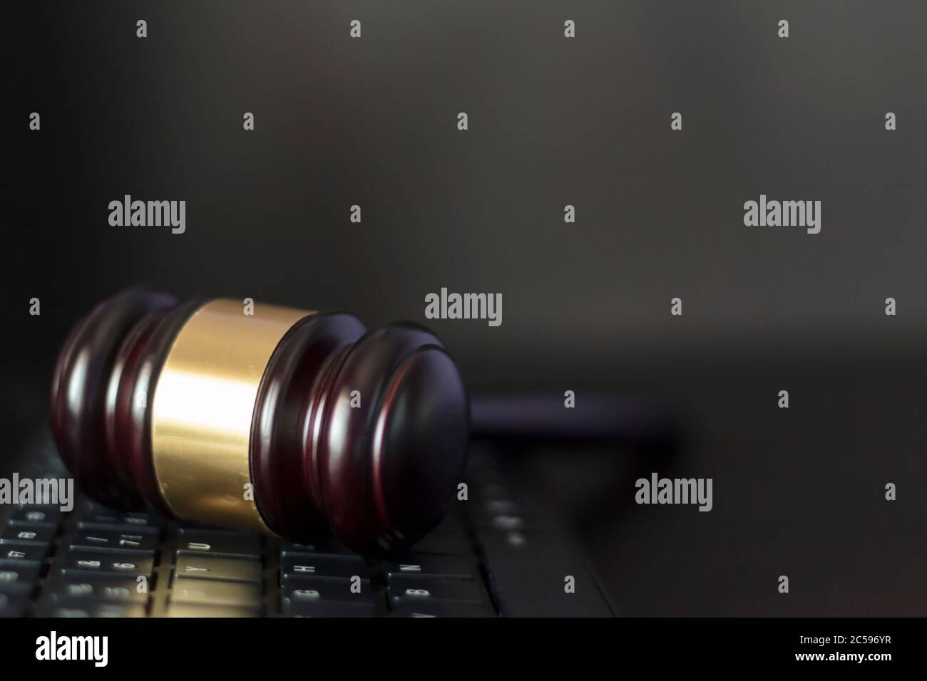 Judge's gavel on computer keyboard on black background with copy space. Cyber crime, law and ...