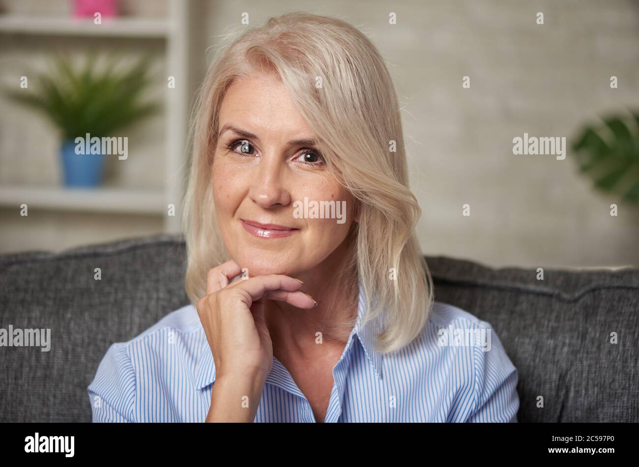 Beautiful 50 years old woman relaxing on sofa at home Stock Photo - Alamy