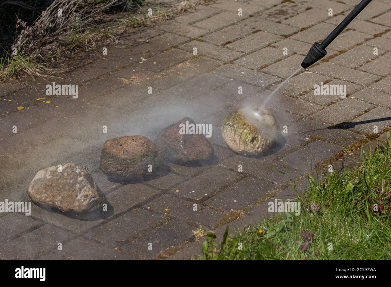 high-pressure washer cleans stones on garden lane of country house ...