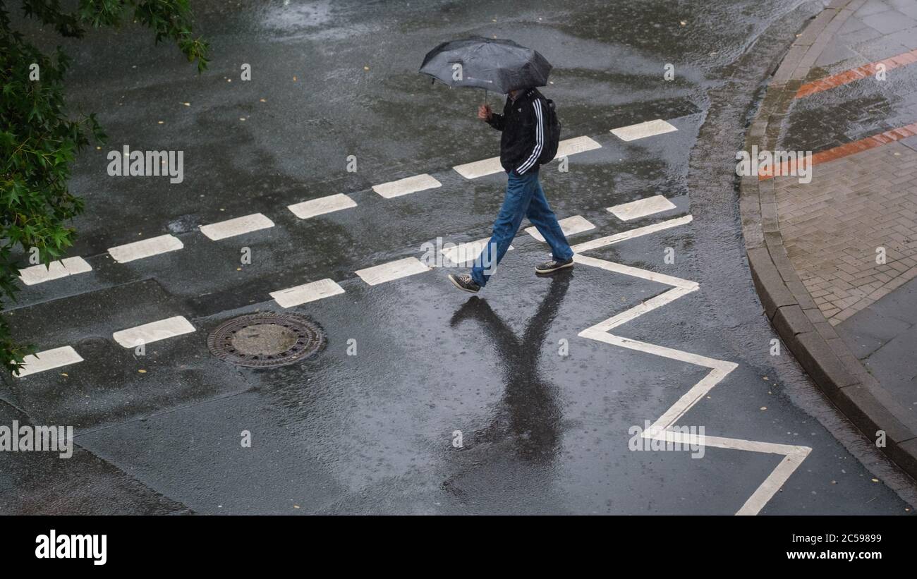Berlin, Germany. 01st July, 2020. A passer-by walks through the pouring ...