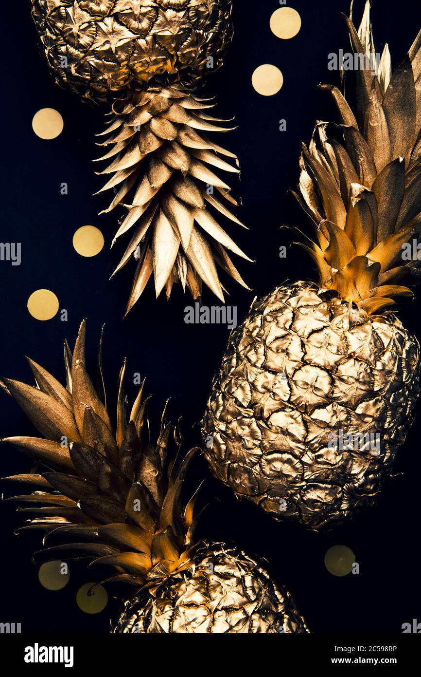 Flat lay tropical gold pineapple and confetti on a dark background ...