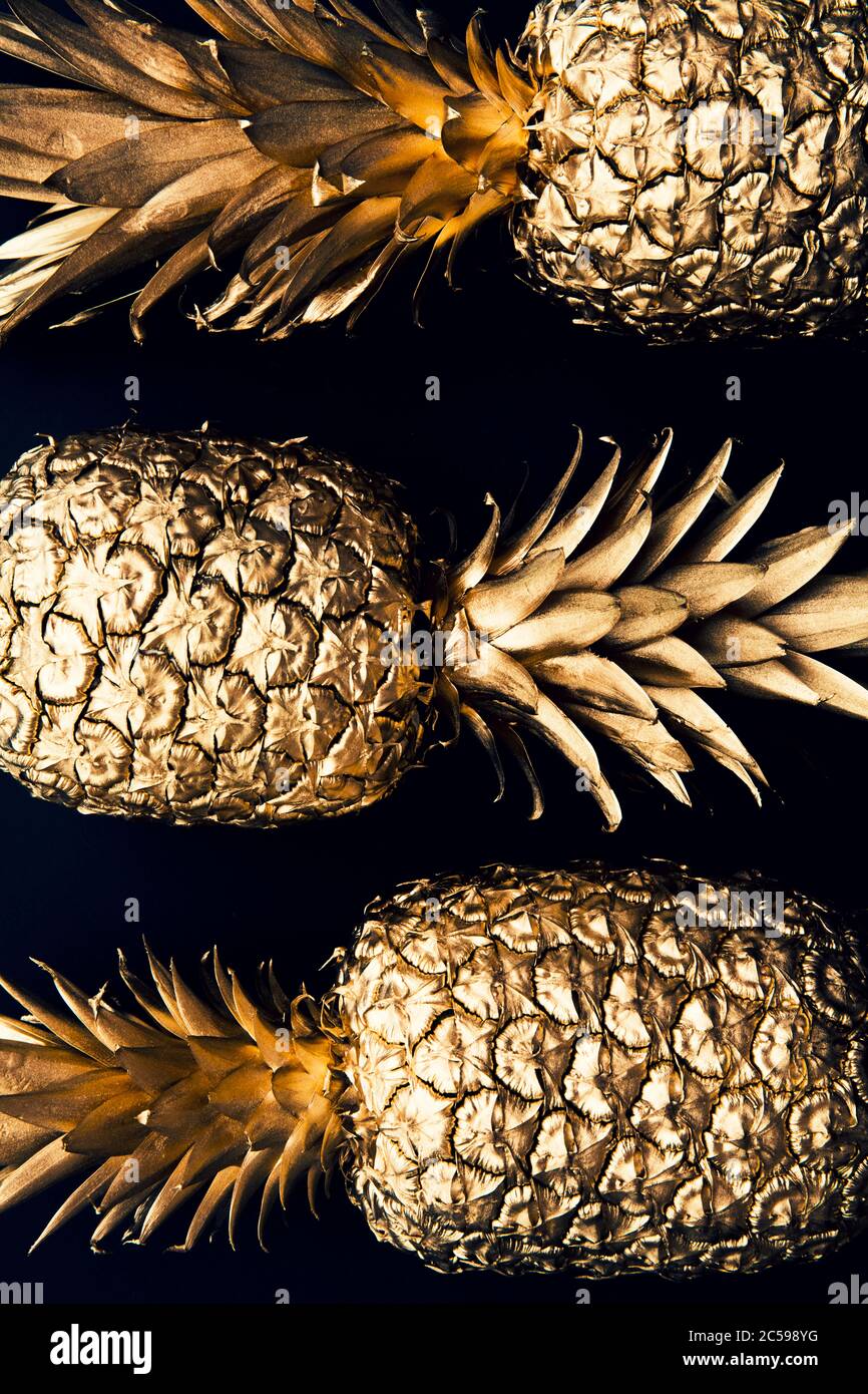 Flat lay tropical gold pineapples on a dark background Stock Photo - Alamy