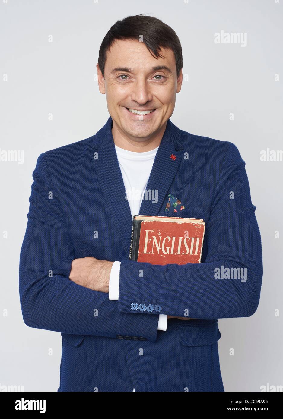 Happy handsome man holds a textbook. learning english. Isolated on grey ...