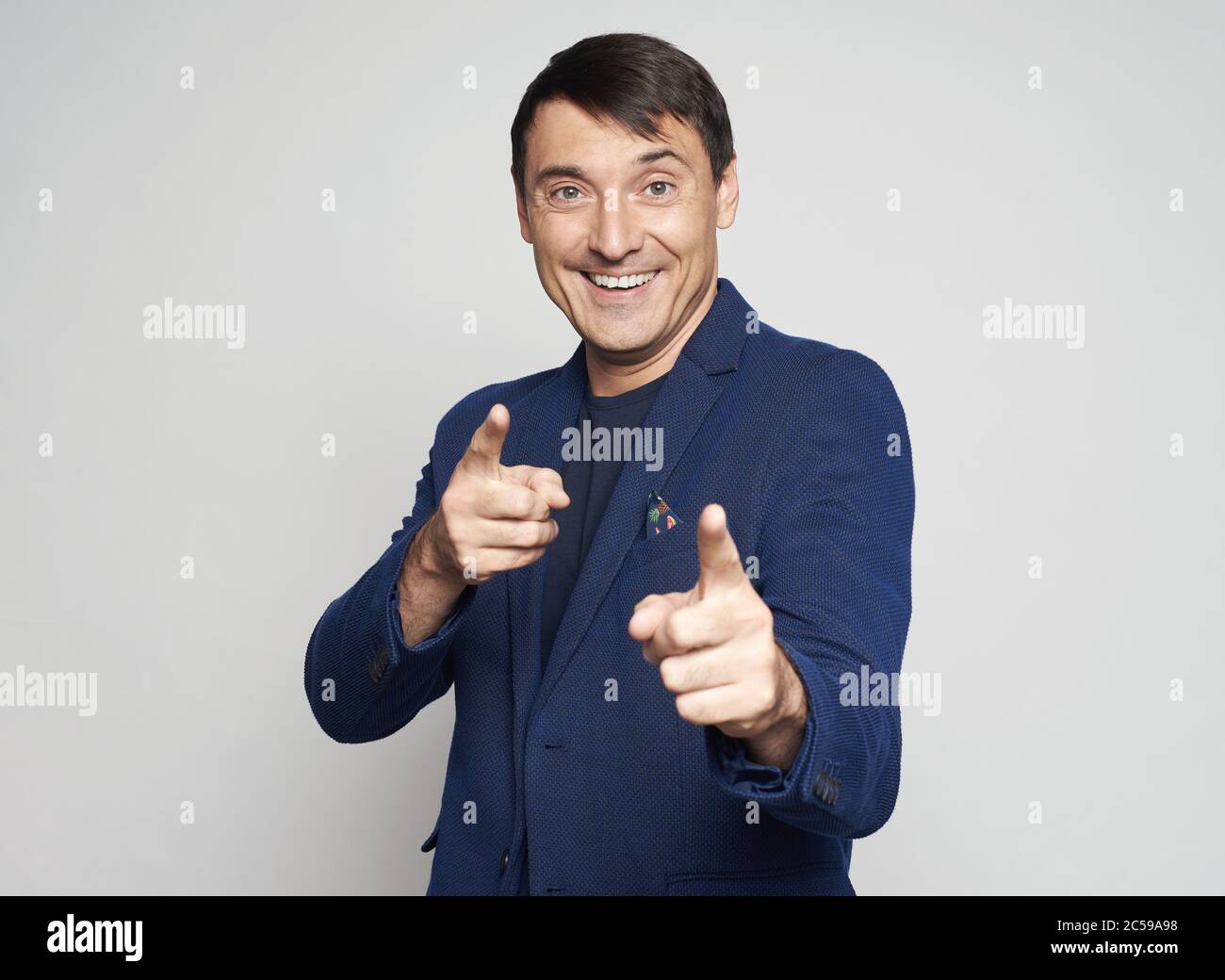 Handsome business man pointing finger at you isolated on grey studio ...