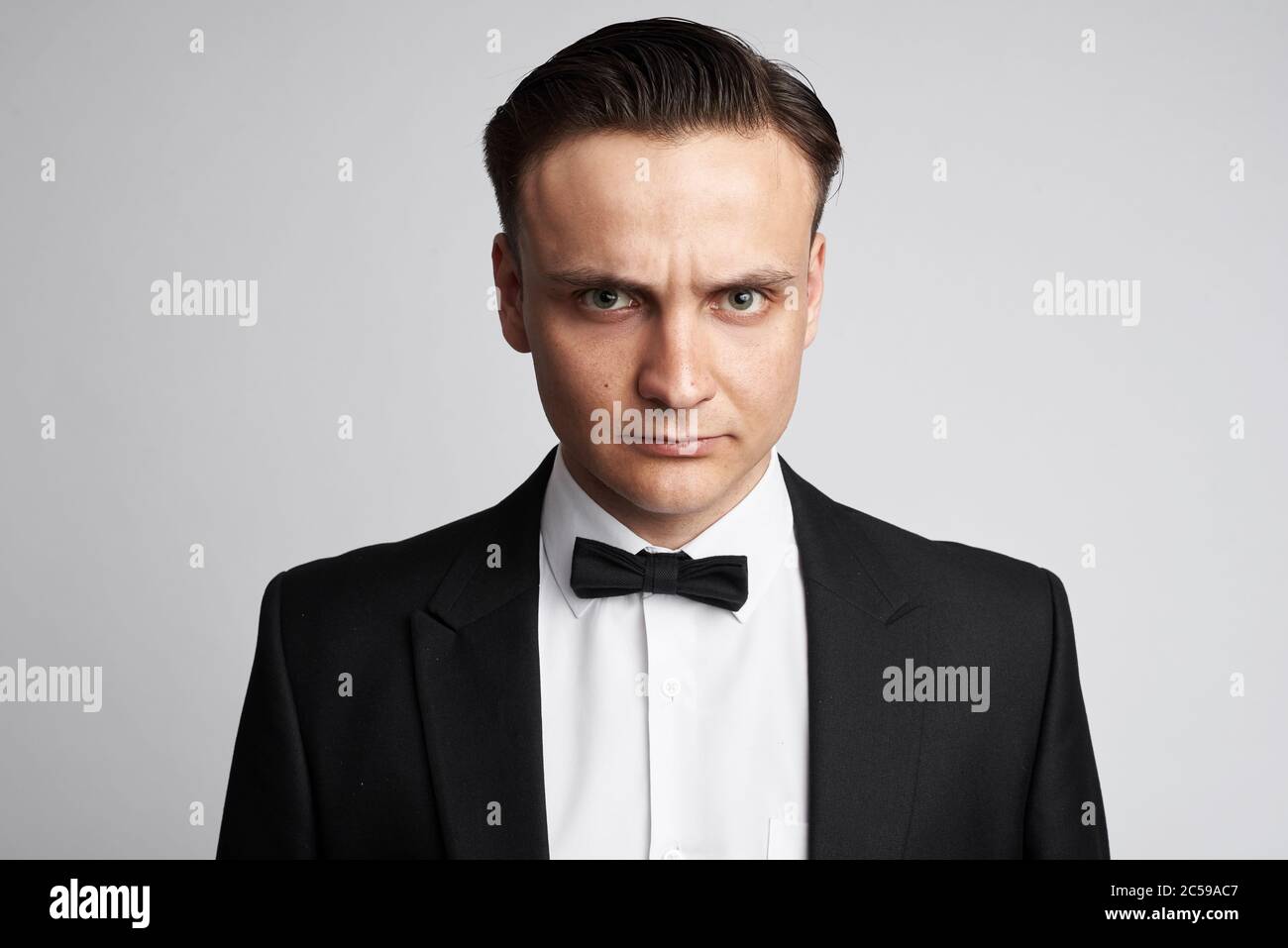 Fashionable young man wearing suit and bow tie. Angry guy studio shot ...