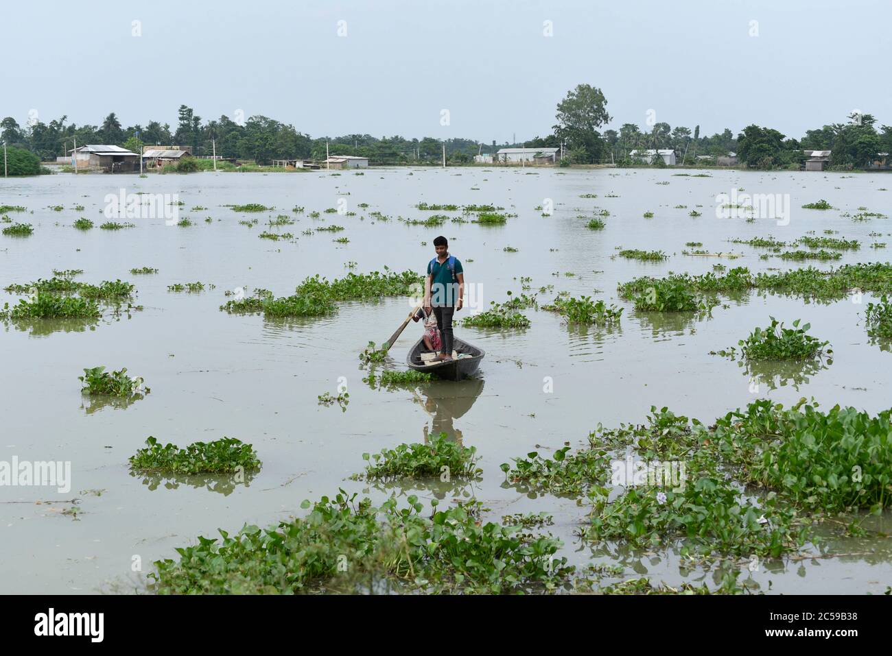 Morigaon, Assam, India. 1st July, 2020. Villagers cross a flooded area ...