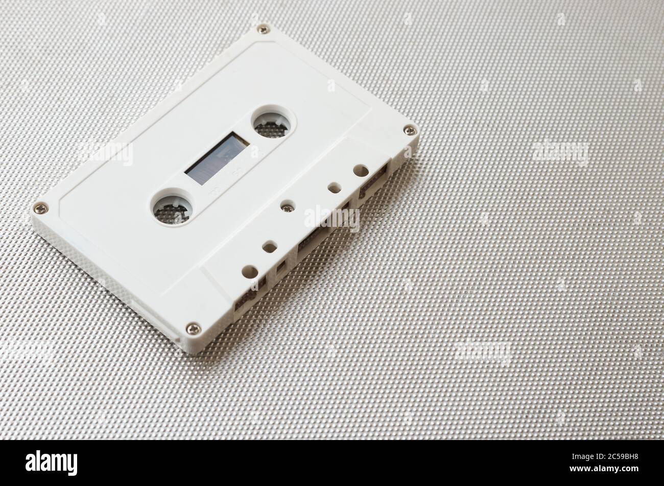 White audio cassette without markings isolated on metal backdrop. Close ...