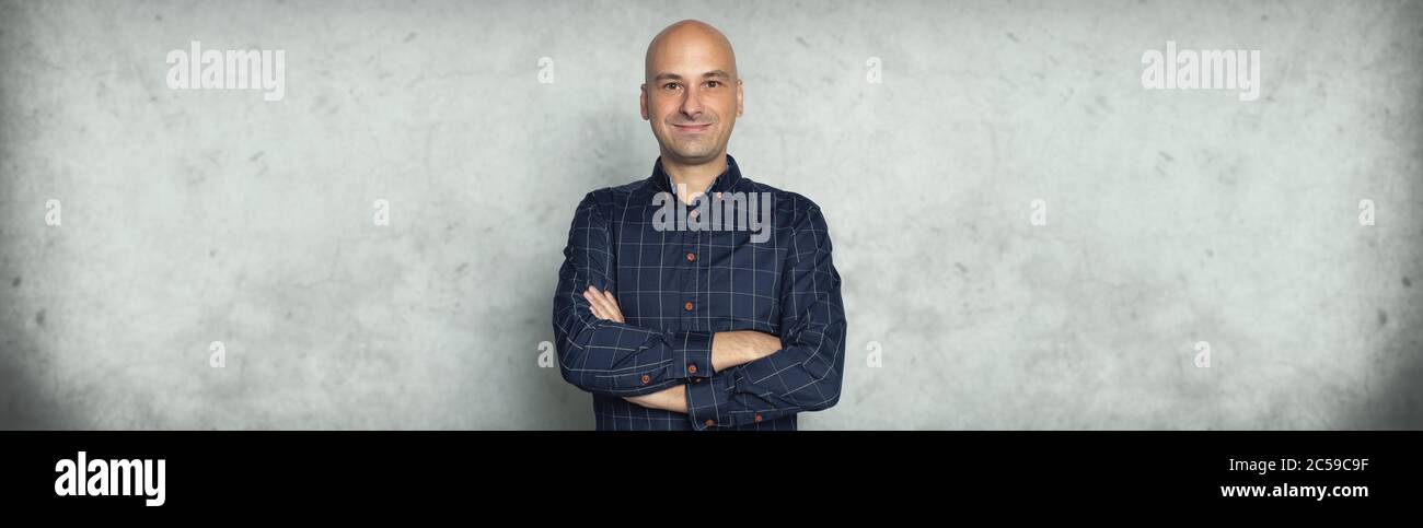 happy bald man smiling standing near grey stone wall. Studio shot with ...