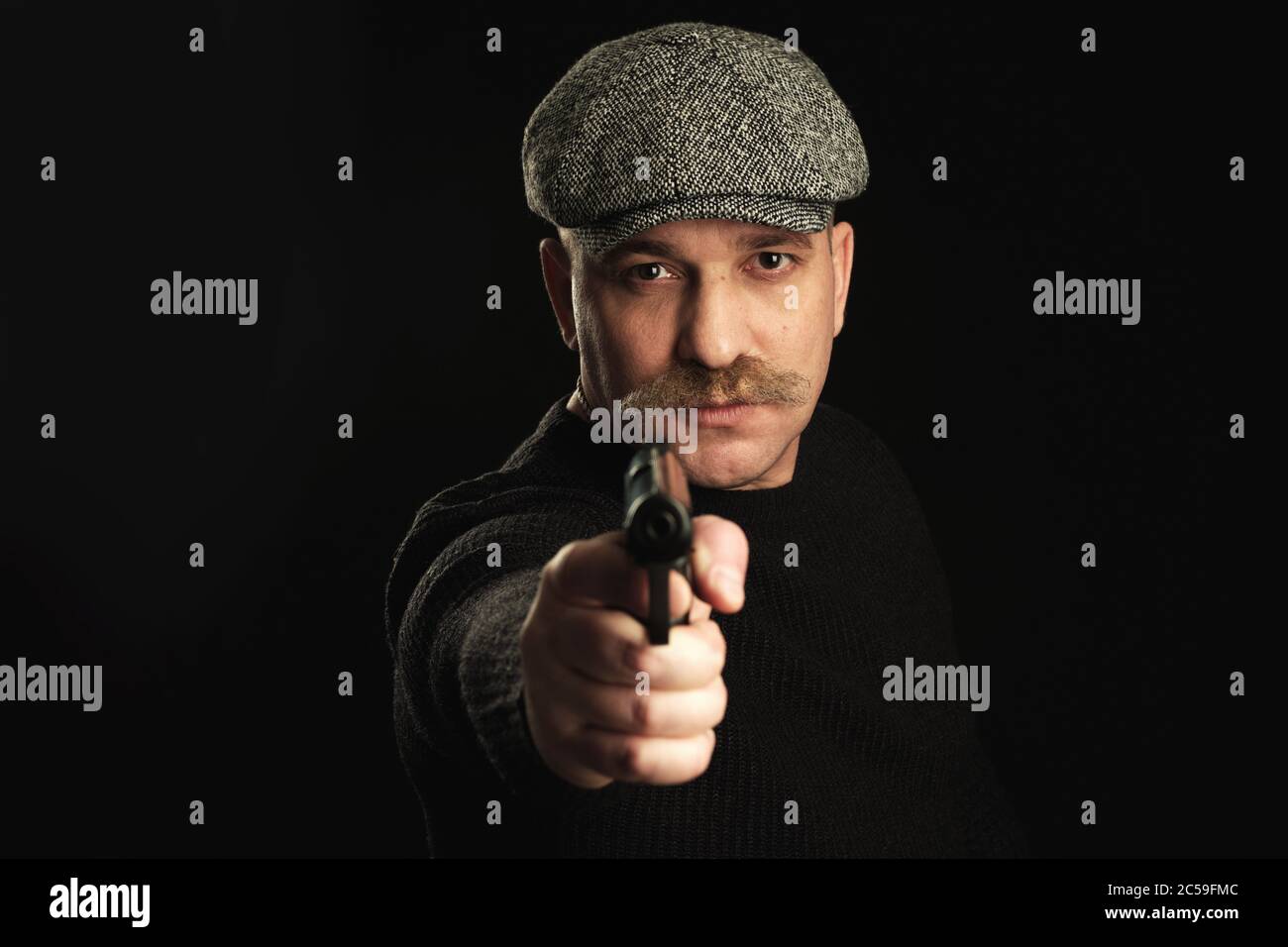 man pointing a gun at the camera over black studio background Stock ...