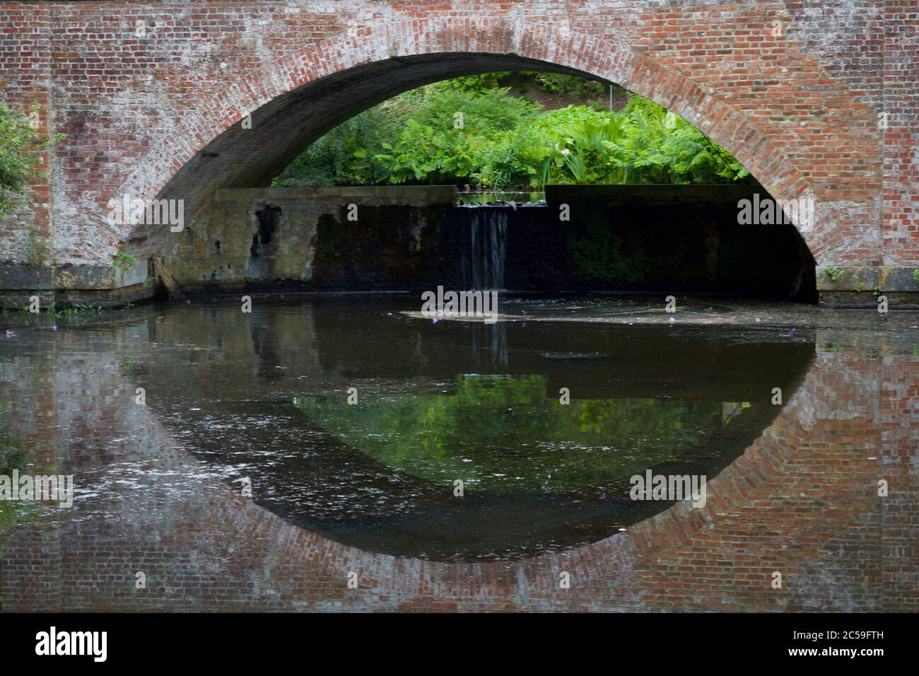 Old arched bridge over pond with foliage all reflected in water Stock ...