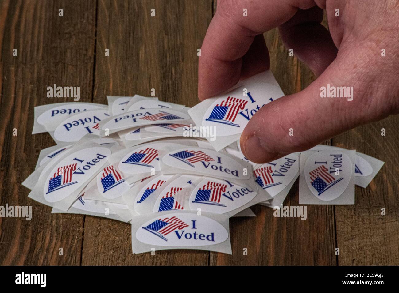 Denver, CO--June 30, 2020; voter hand reaching into a pile of red white ...
